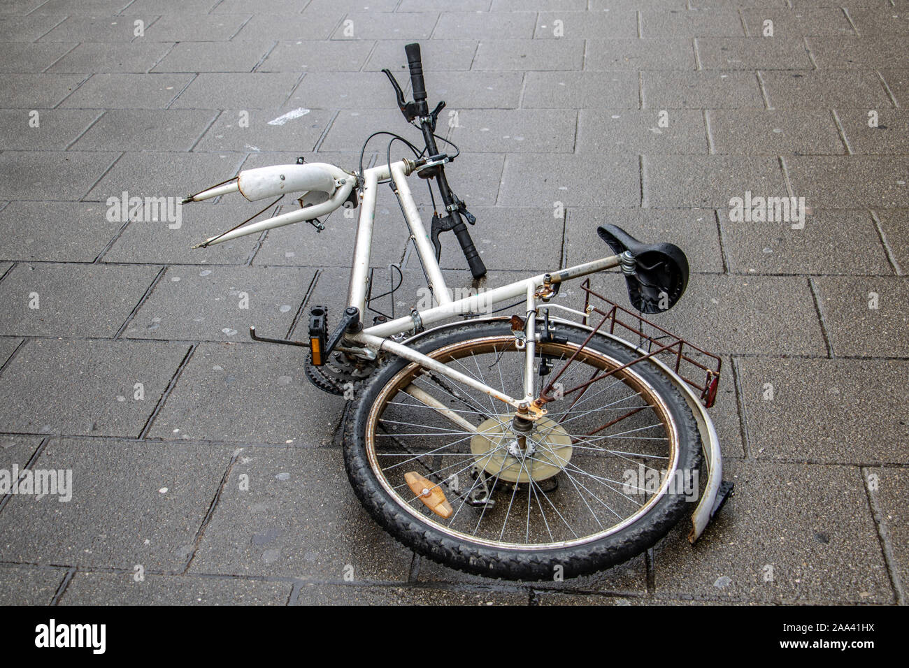 The damaged bicycle lying on the street in the city center. The ...