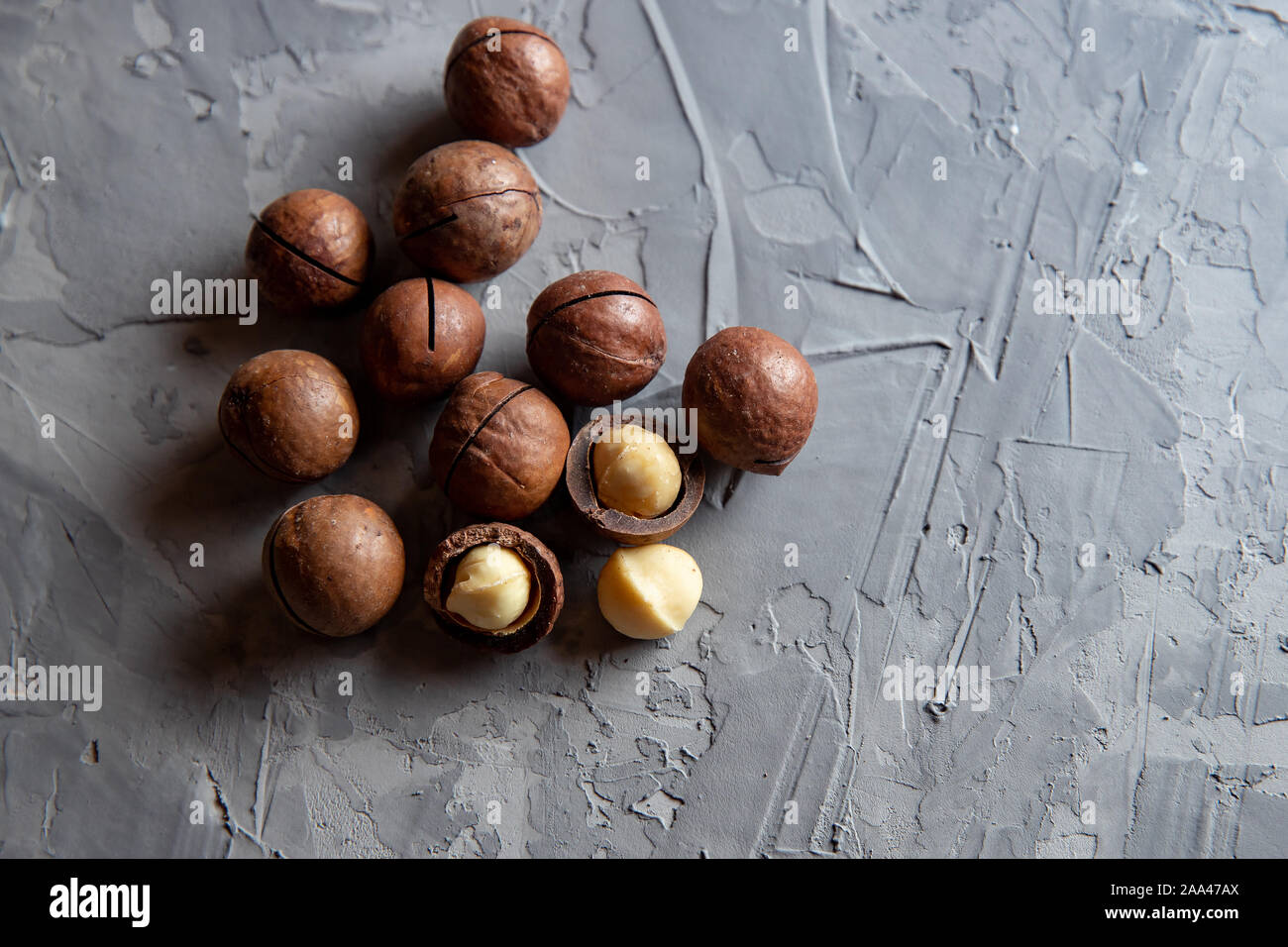 Pile macadamia nuts open kernels and shells on gray concrete background ...