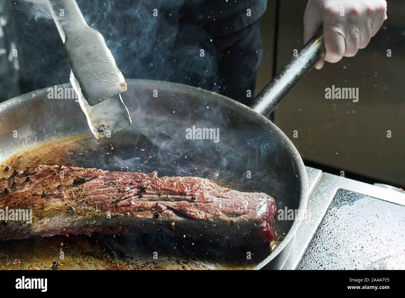 The chef works in the kitchen of the restaurant. Fresh meat roasted in ...