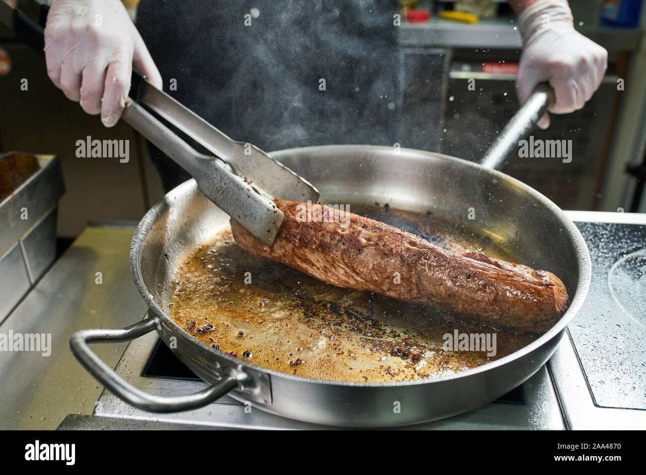 The chef works in the kitchen of the restaurant. Fresh meat roasted in ...