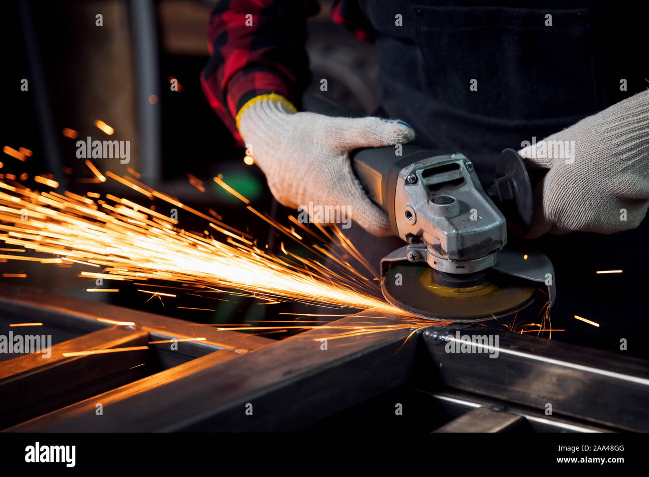 Worker hand with electric wheel grinding on steel structure in factory ...