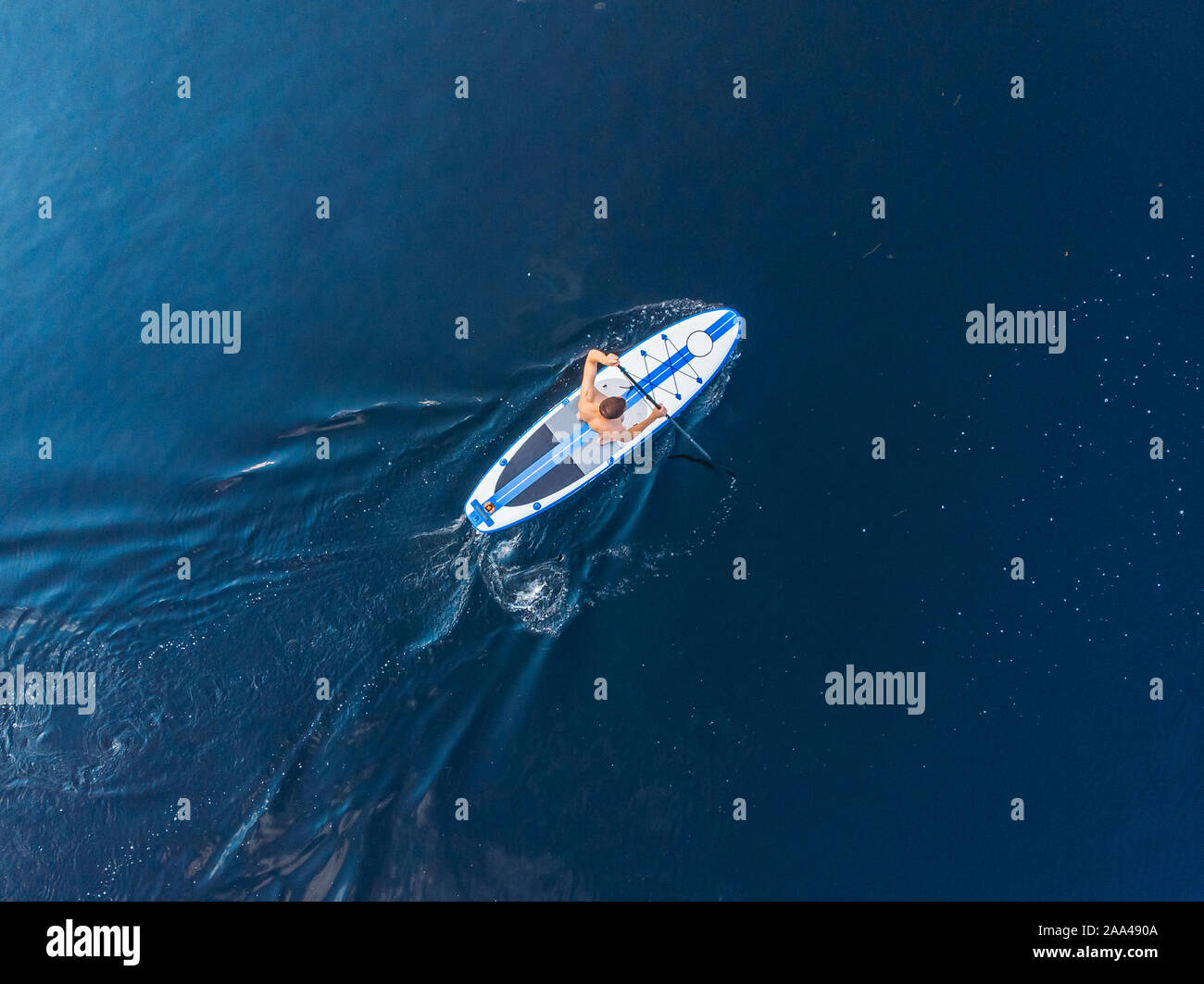 Man rowing oar on sup board blue sea water. Aerial top view paddleboard ...