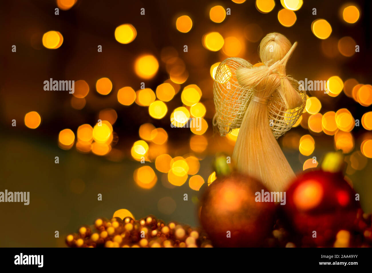 Traditional hand made straw doll with Christmas ornaments on a blurred ...