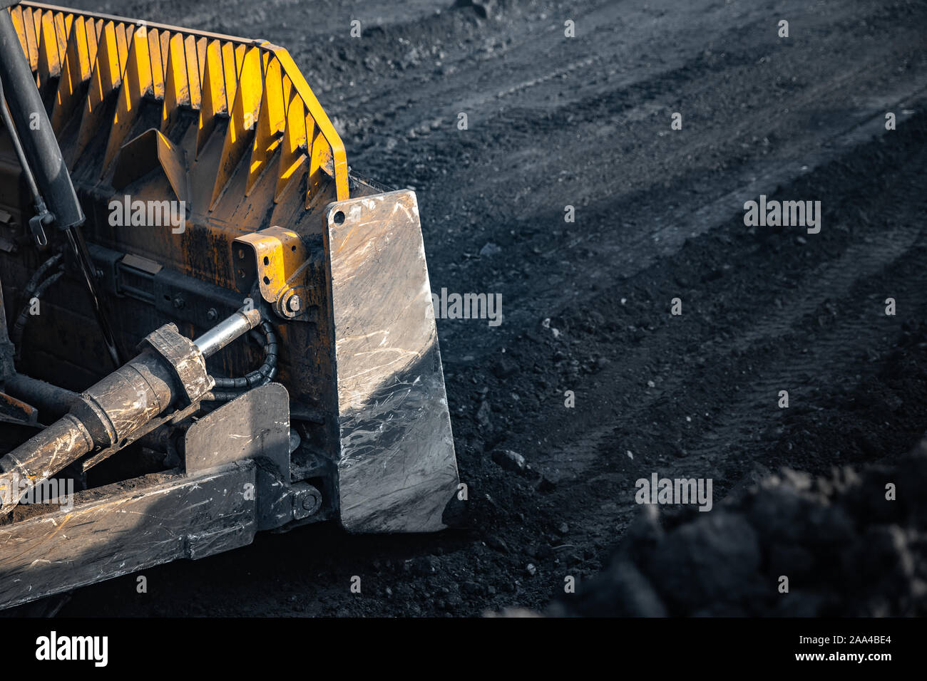 Excavator levels coal with iron bucket, grader paves road after ...