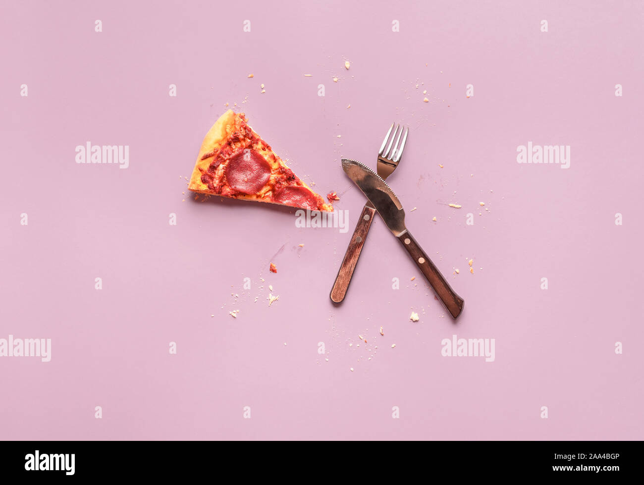Last pizza slice and dinner cutlery, on a purple background with crust ...