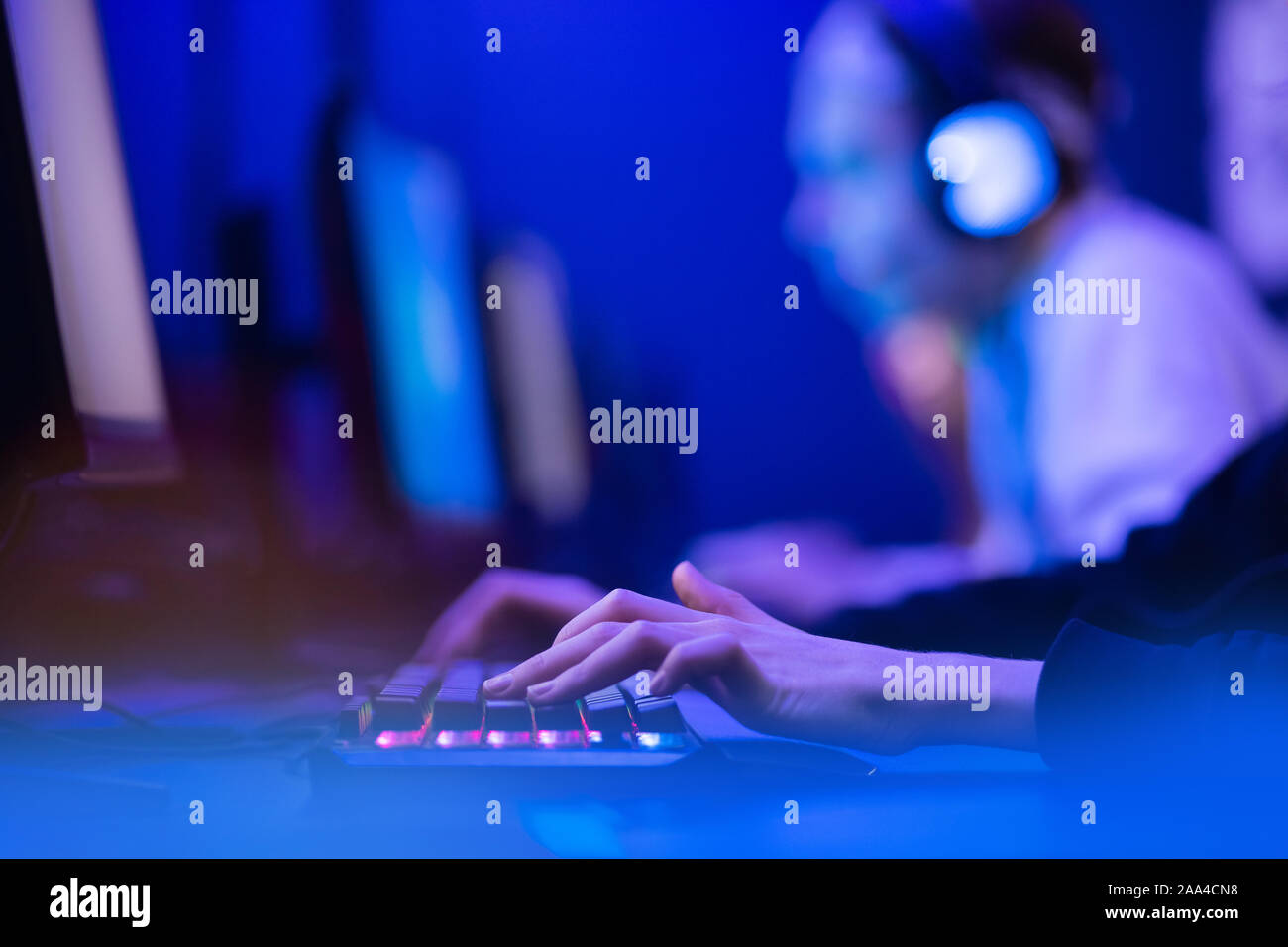 Professional online gamer hand fingers mechanical keyboard in neon ...