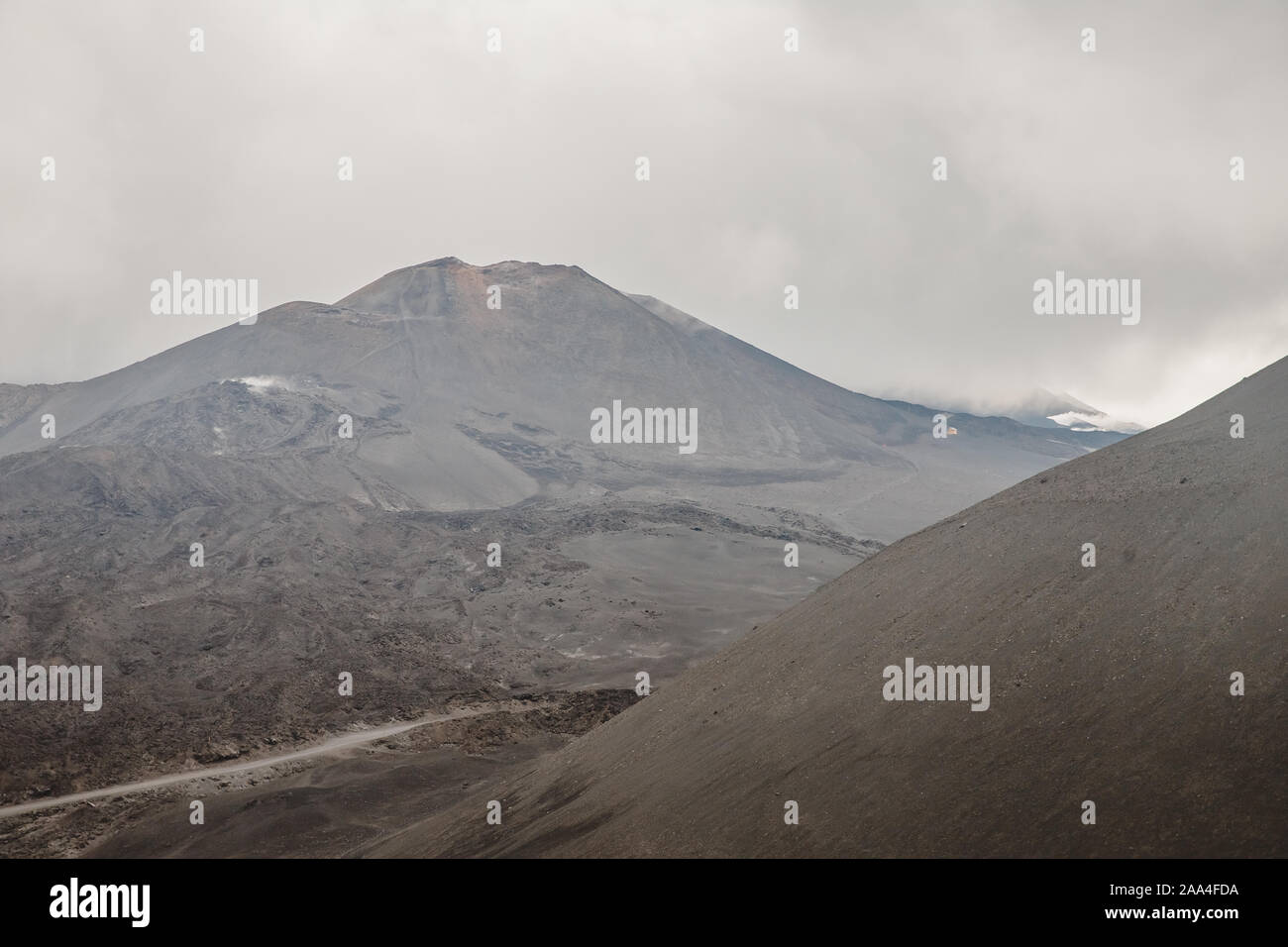 Top of crater Mount Etna volcano, frozen cold lava smokes, thick clouds ...