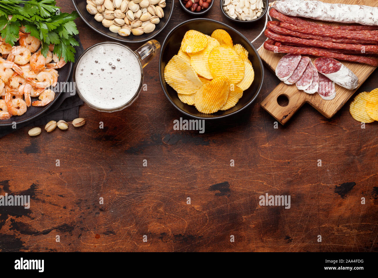 Draft beer and snacks on wooden background. Nuts, chips, sausages and ...