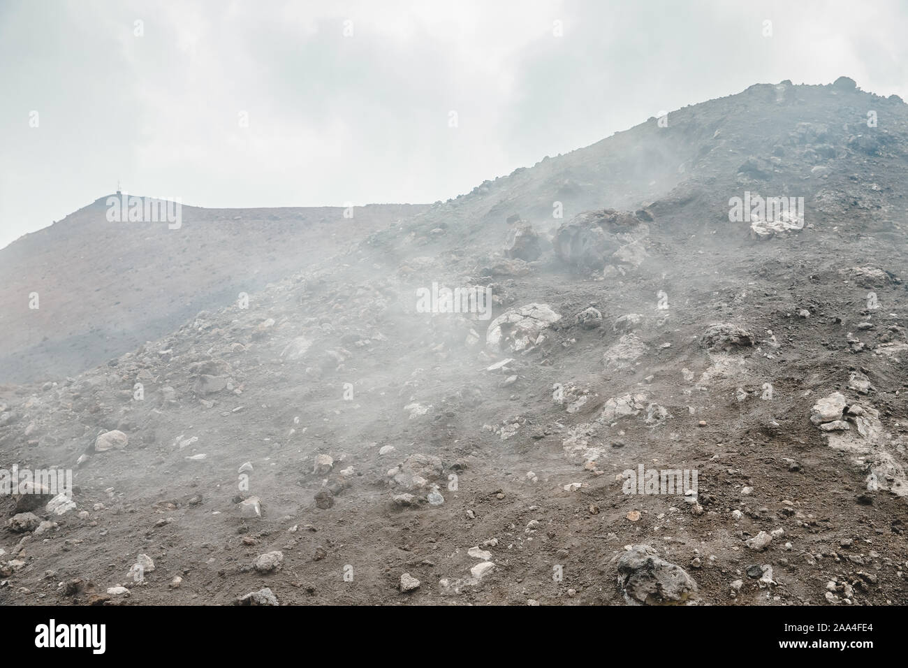 Top of crater Mount Etna volcano, frozen cold lava smokes, thick clouds ...