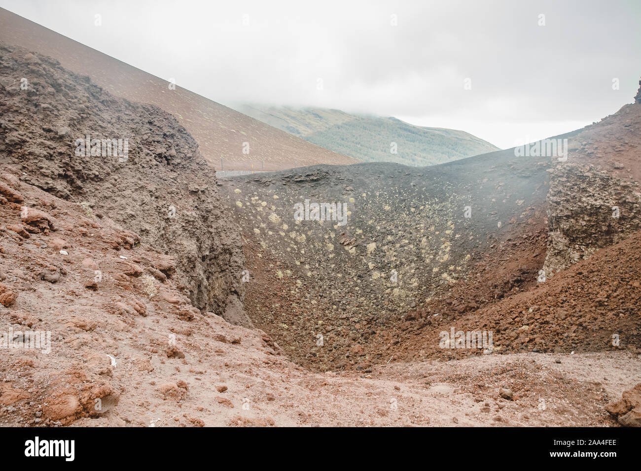 Top of crater Mount Etna volcano, frozen cold lava smokes, thick clouds ...