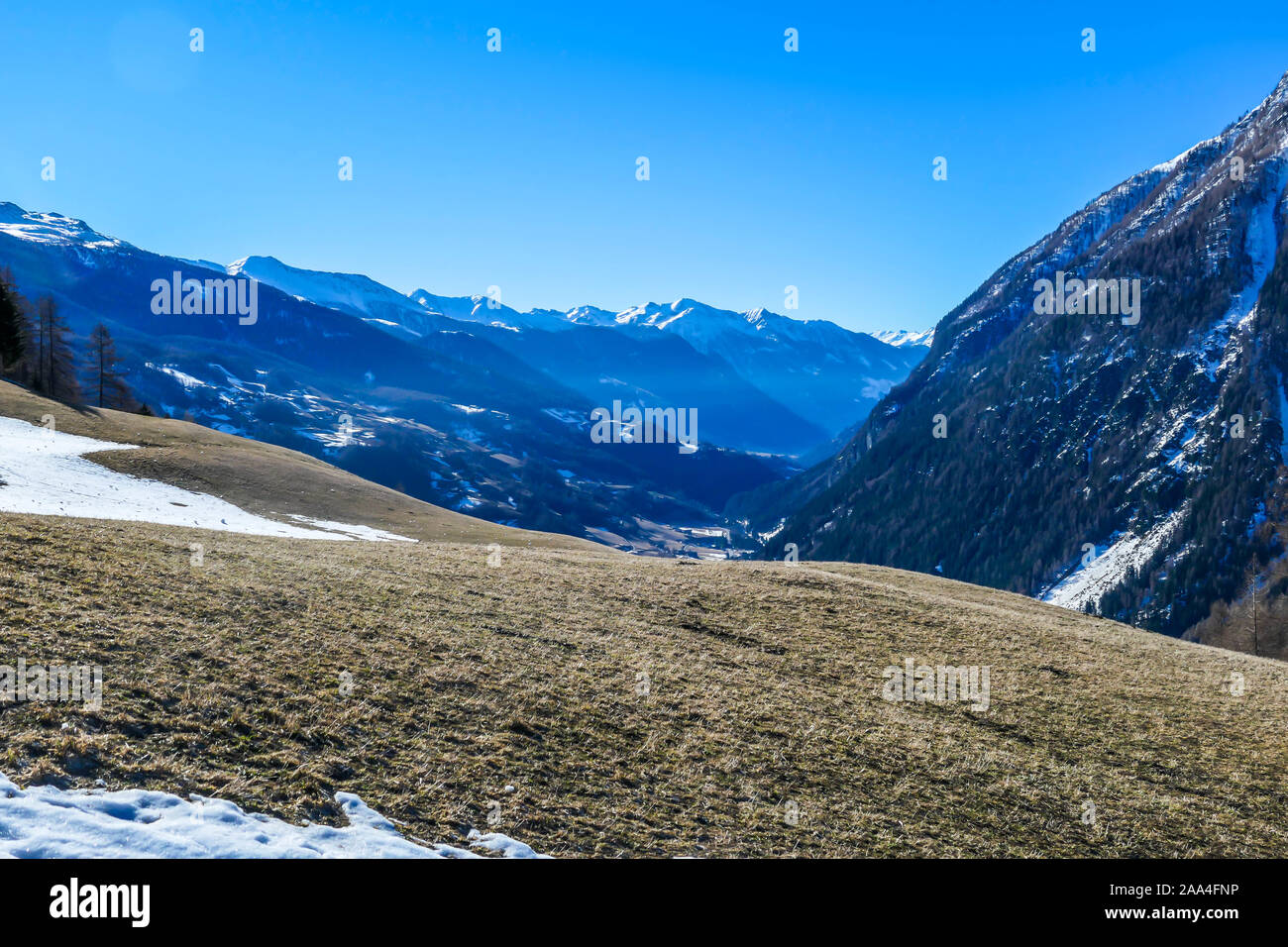 Spring slowly coming to tall Alps. Slopes are partially covered with ...