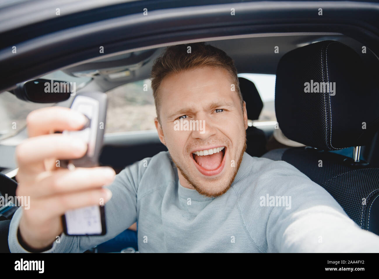 Handsome young man driver smiling making selfie sitting in new car ...