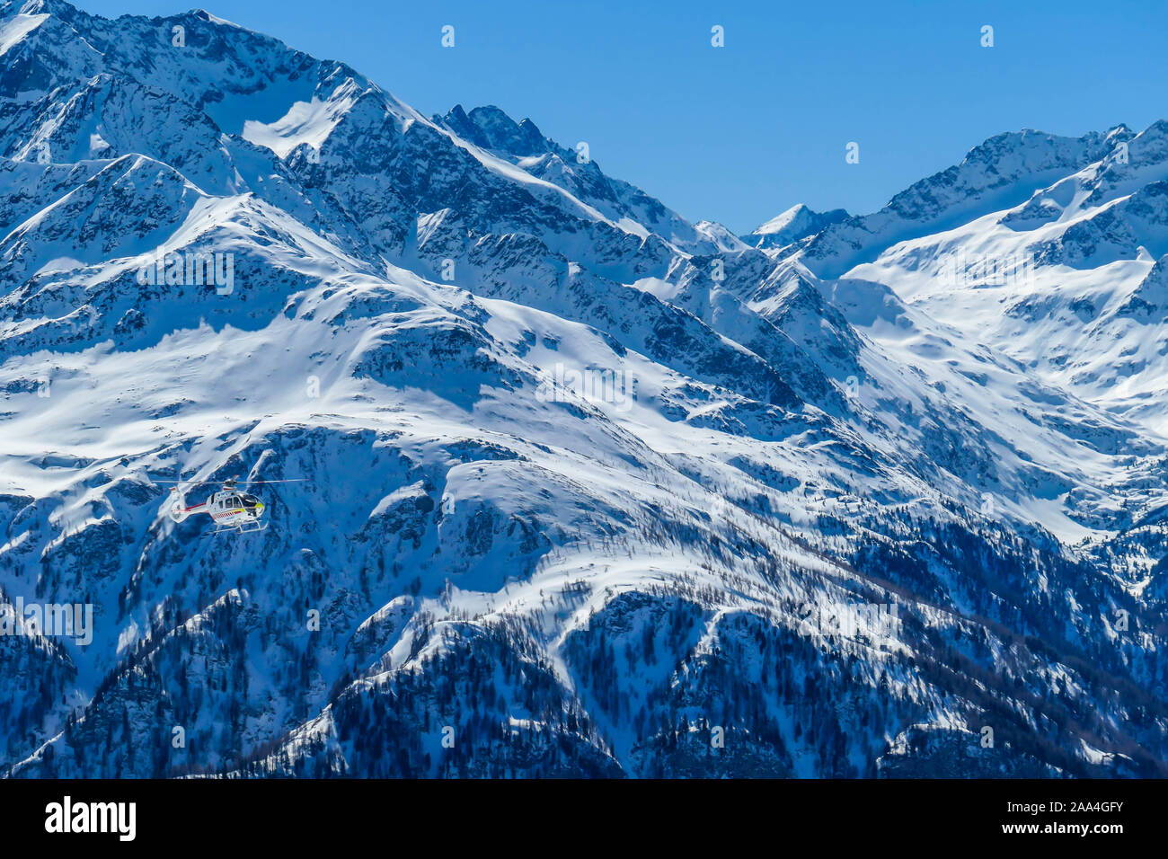 A rescue helicopter in the high mountains. Tall Alps surrounding the ...