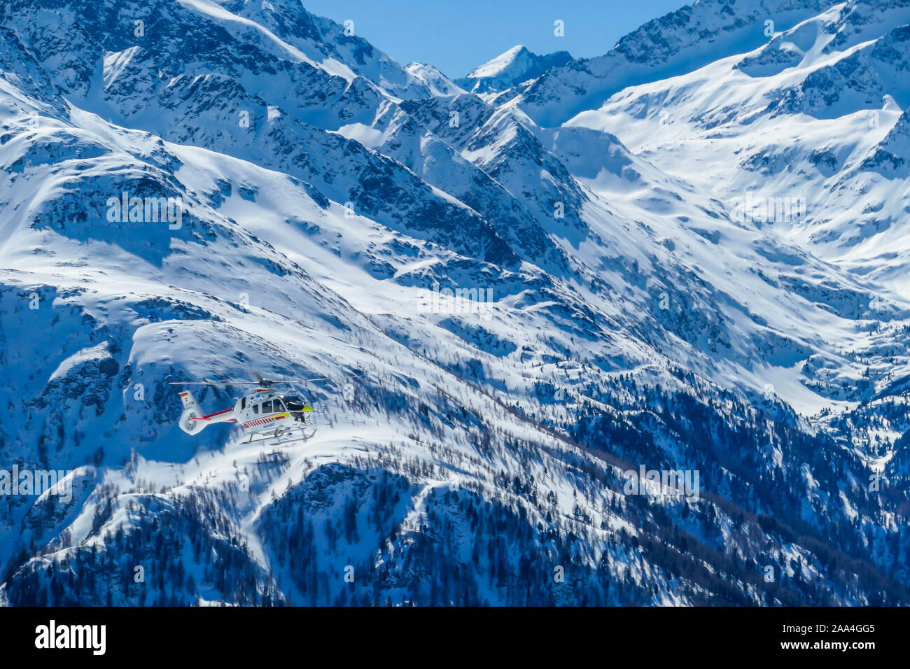 A rescue helicopter in the high mountains. Tall Alps surrounding the ...