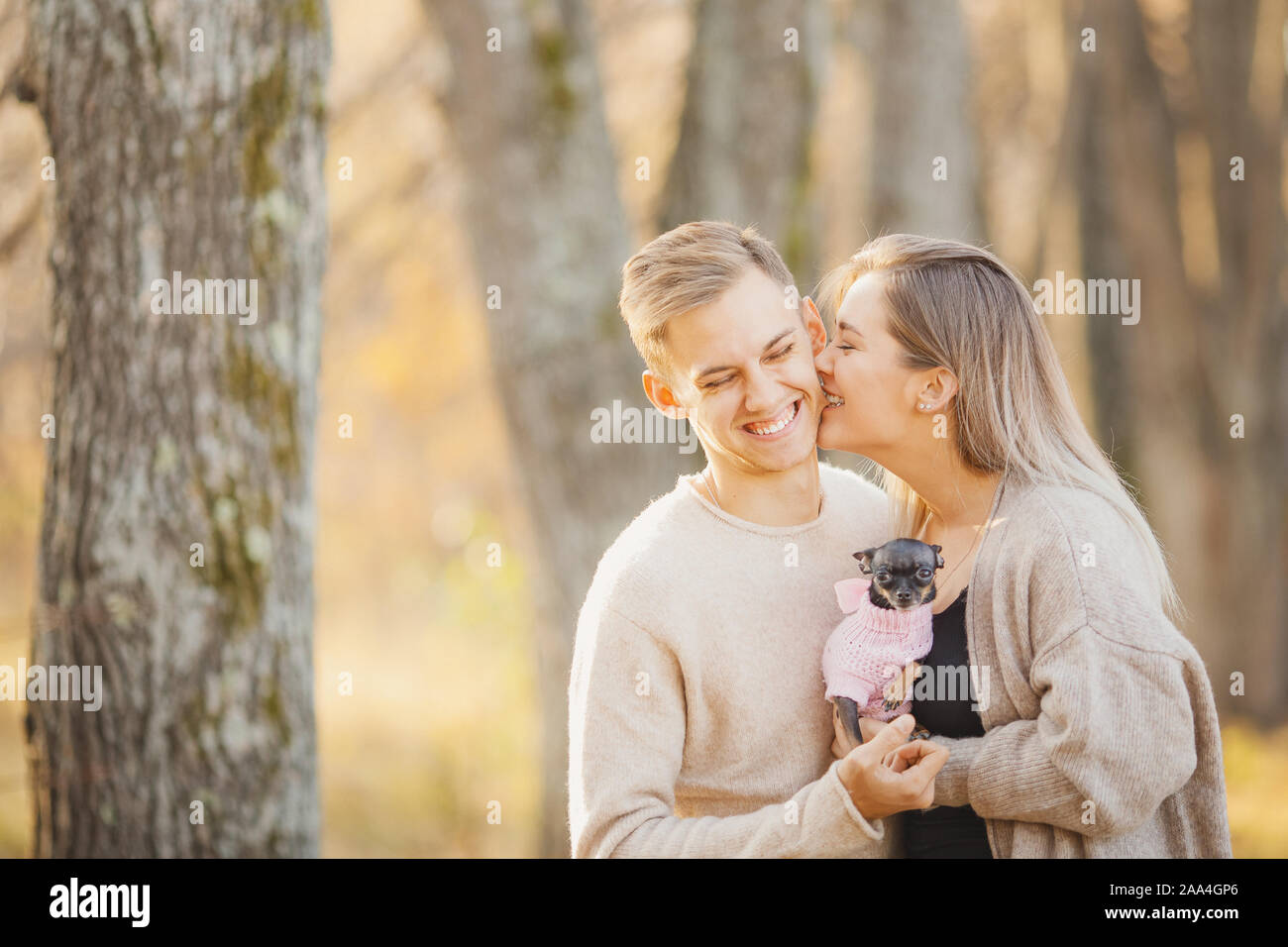Autumn photo, couple in love hugs and holds dwarf dog on background of ...
