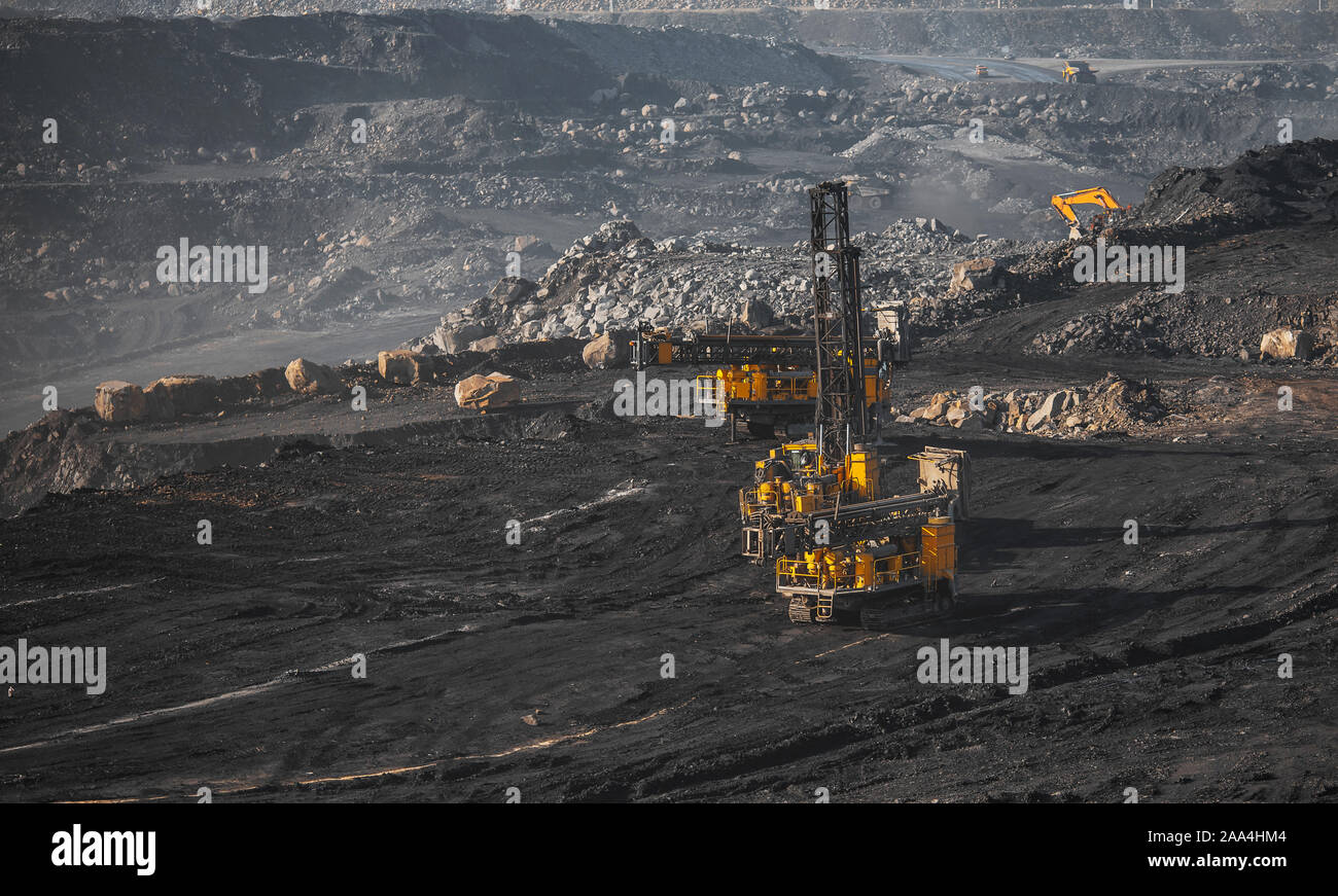 Open coal mine. Drilling machine borer installing cast explosives ...
