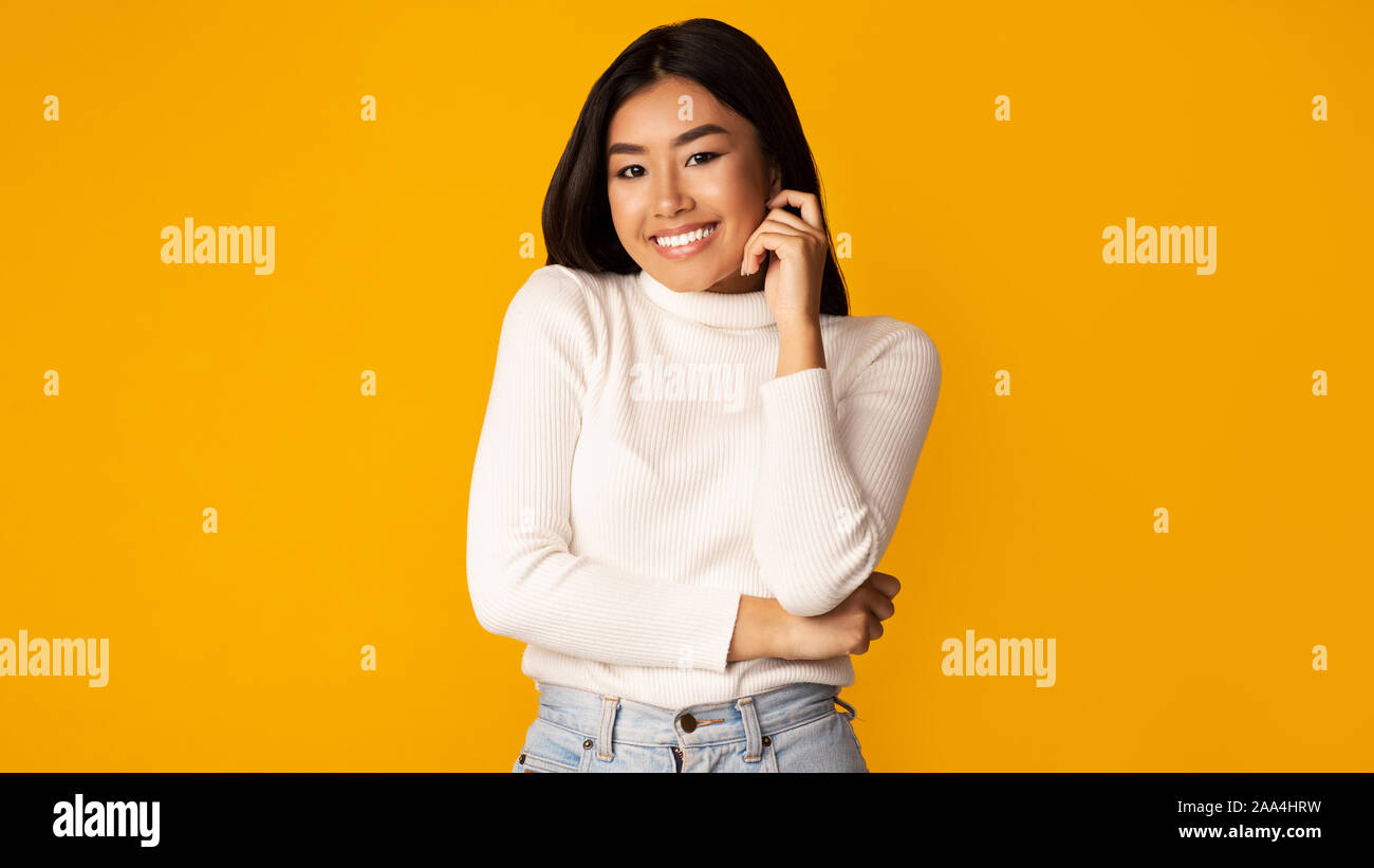 Confident asian girl posing over yellow background Stock Photo - Alamy