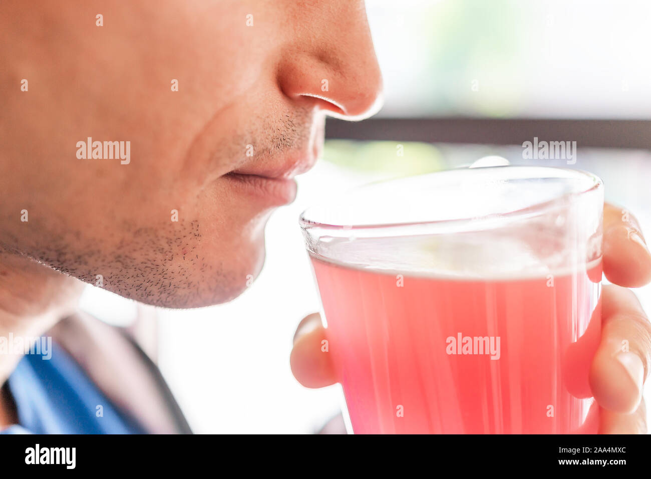 Man face macro closeup of mouth outside holding drinking glass of red ...