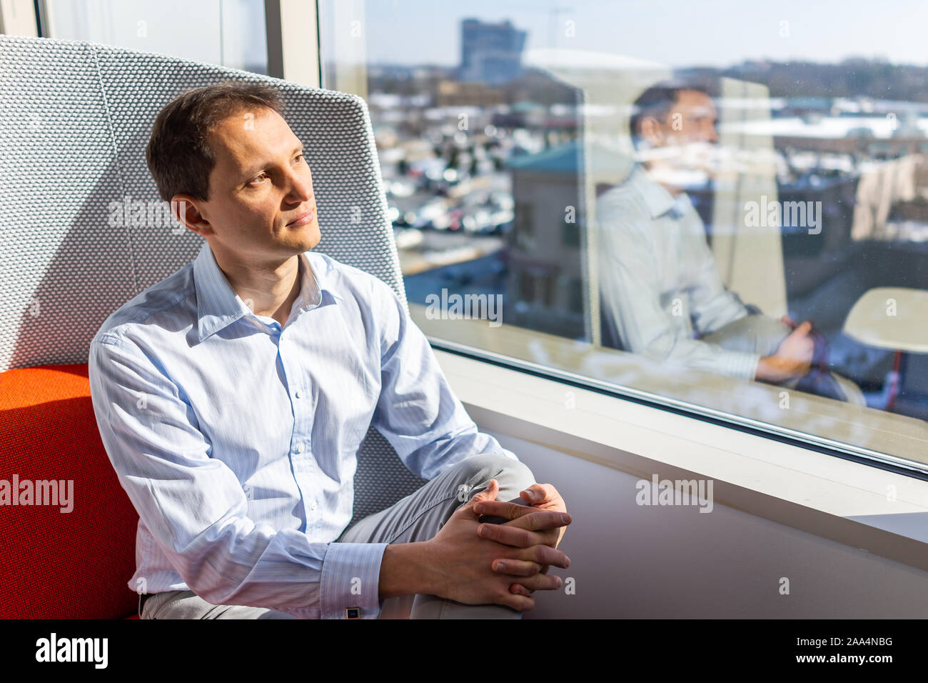 Modern office building with young professional man sitting on chair by ...