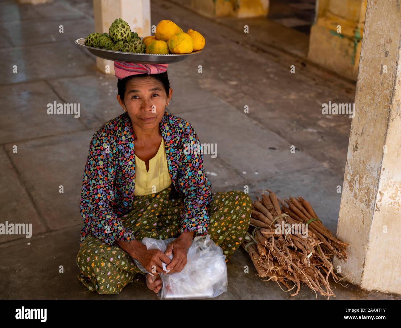 Burmese woman selling custard apples and oranges which she balances on ...