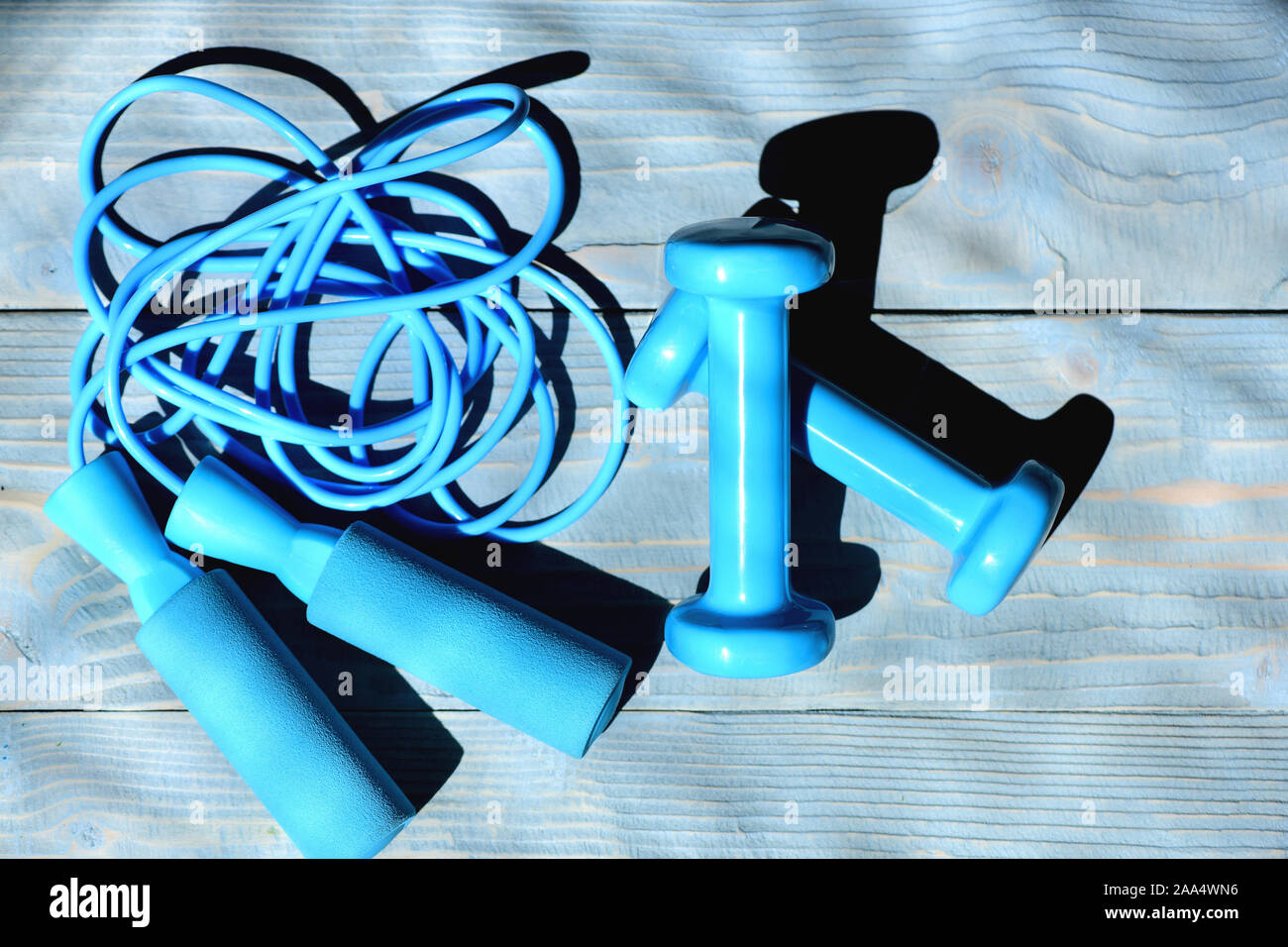 Barbells and messy skipping rope placed crosswise. Shaping and fitness ...