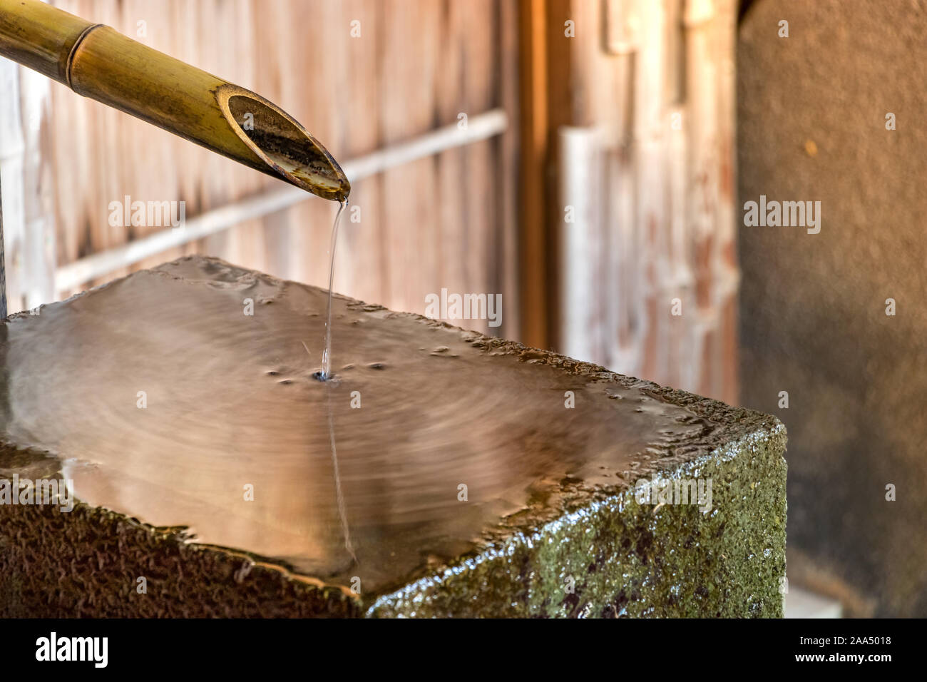 A Chozubachi - Tsukubai, a bamboo pipe dropping water on a flat stone ...