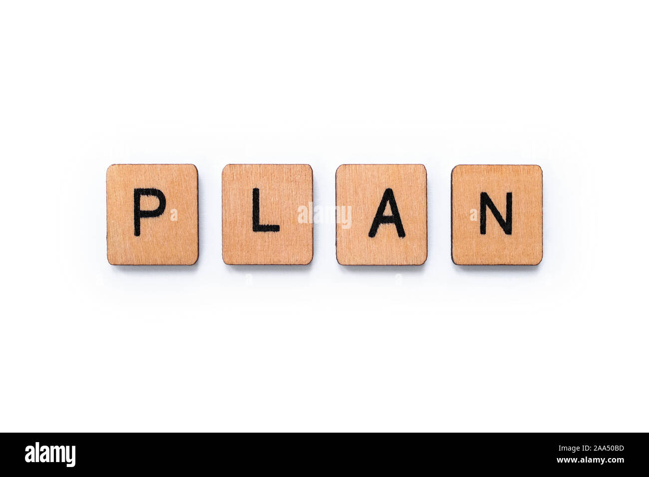 The word PLAN, spelt with wooden letter tiles over a white background ...