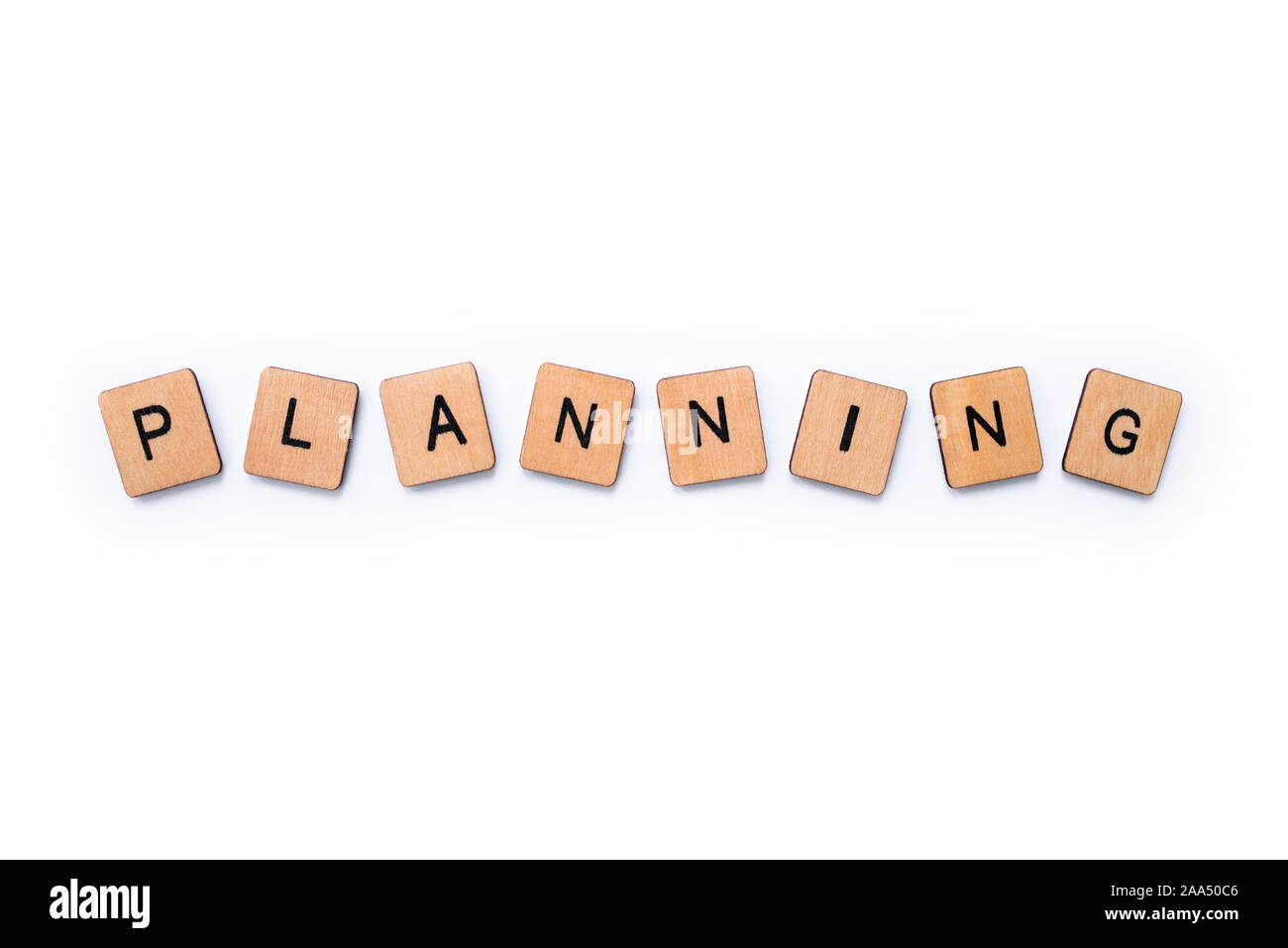 The word PLANNING, spelt with wooden letter tiles over a white ...