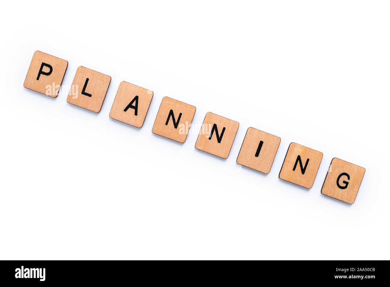 The word PLANNING, spelt with wooden letter tiles over a white ...