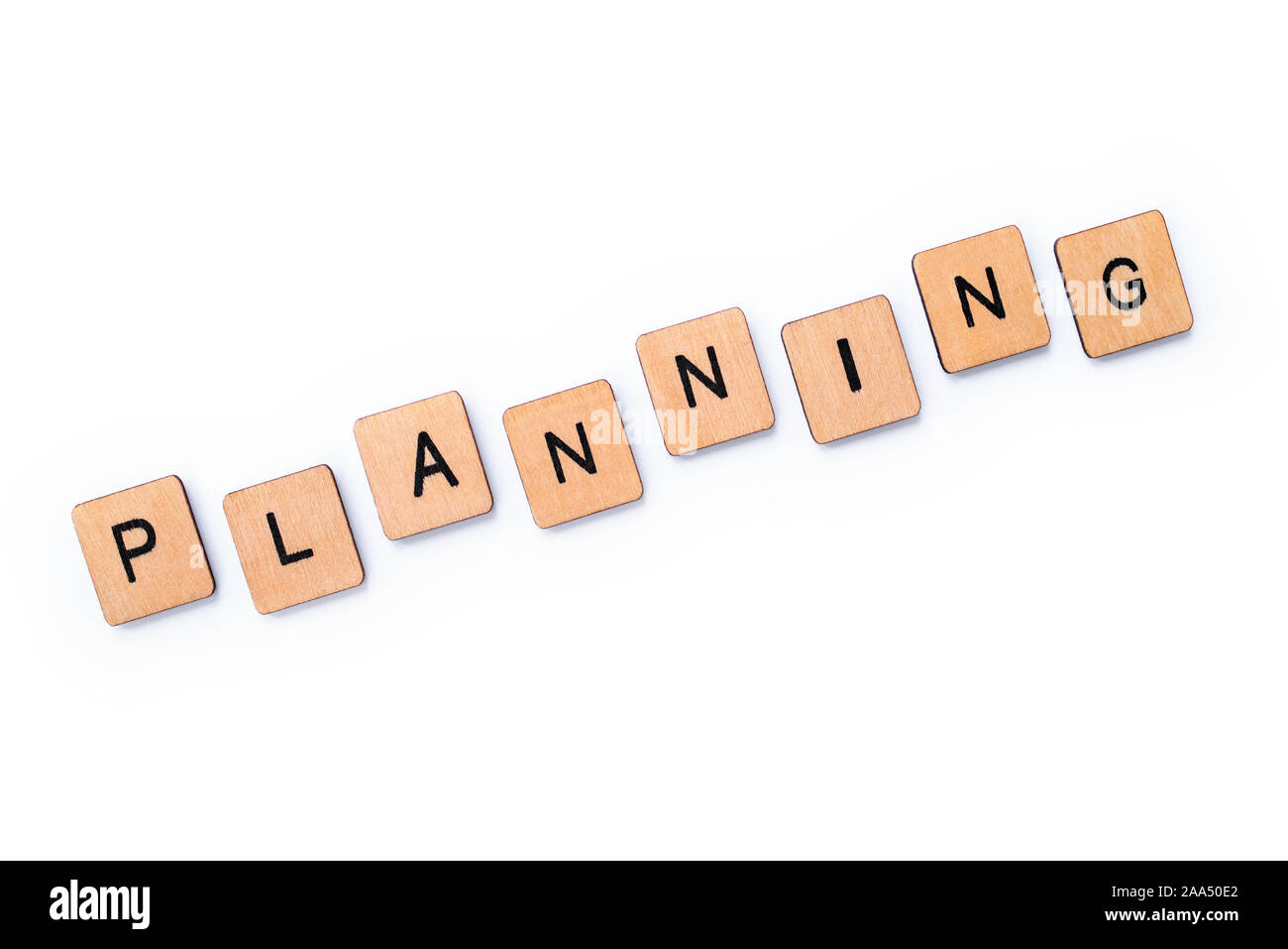 The word PLANNING, spelt with wooden letter tiles over a white ...