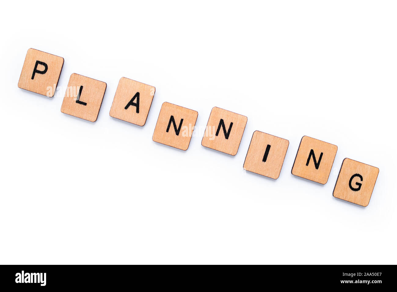 The word PLANNING, spelt with wooden letter tiles over a white ...