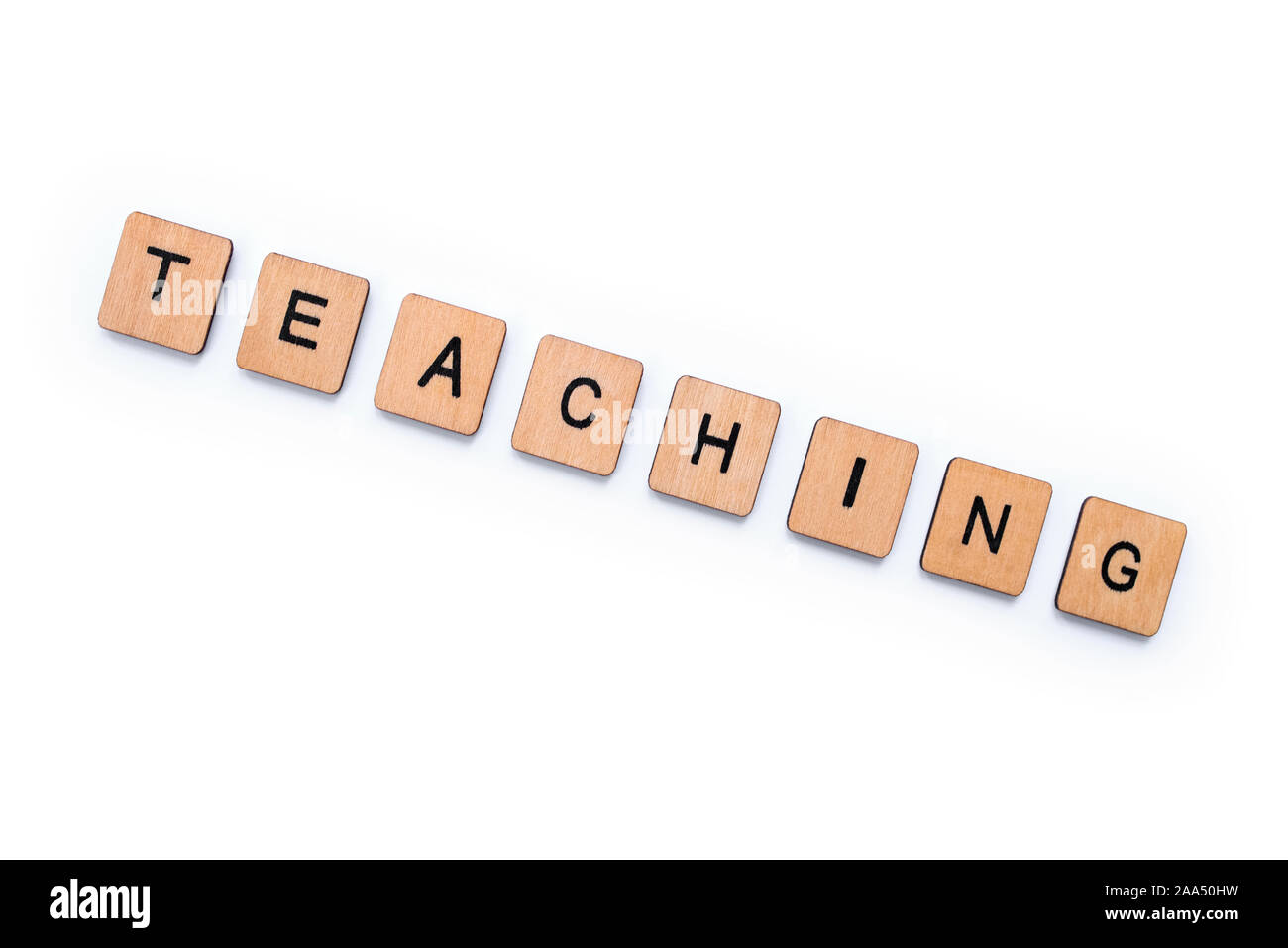 The word TEACHING, spelt with wooden letter tiles over a white ...