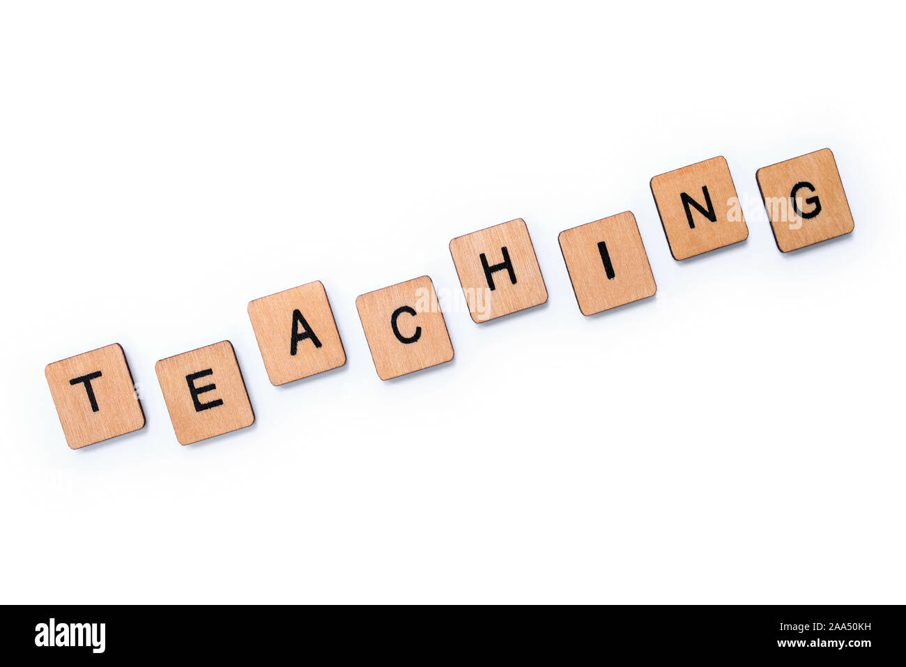 The word TEACHING, spelt with wooden letter tiles over a white ...