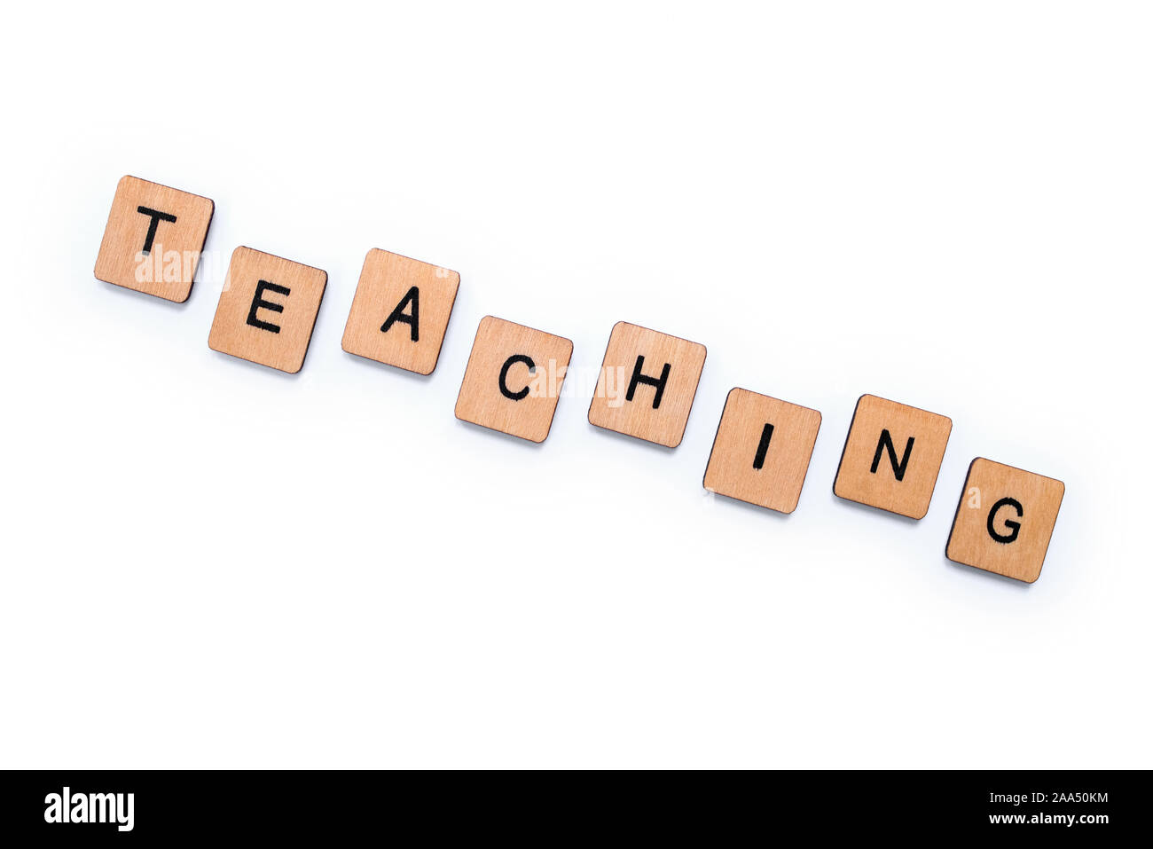 The word TEACHING, spelt with wooden letter tiles over a white ...