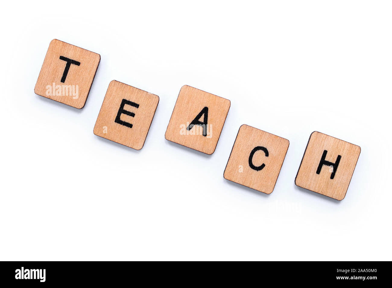 The word TEACH, spelt with wooden letter tiles over a white background ...