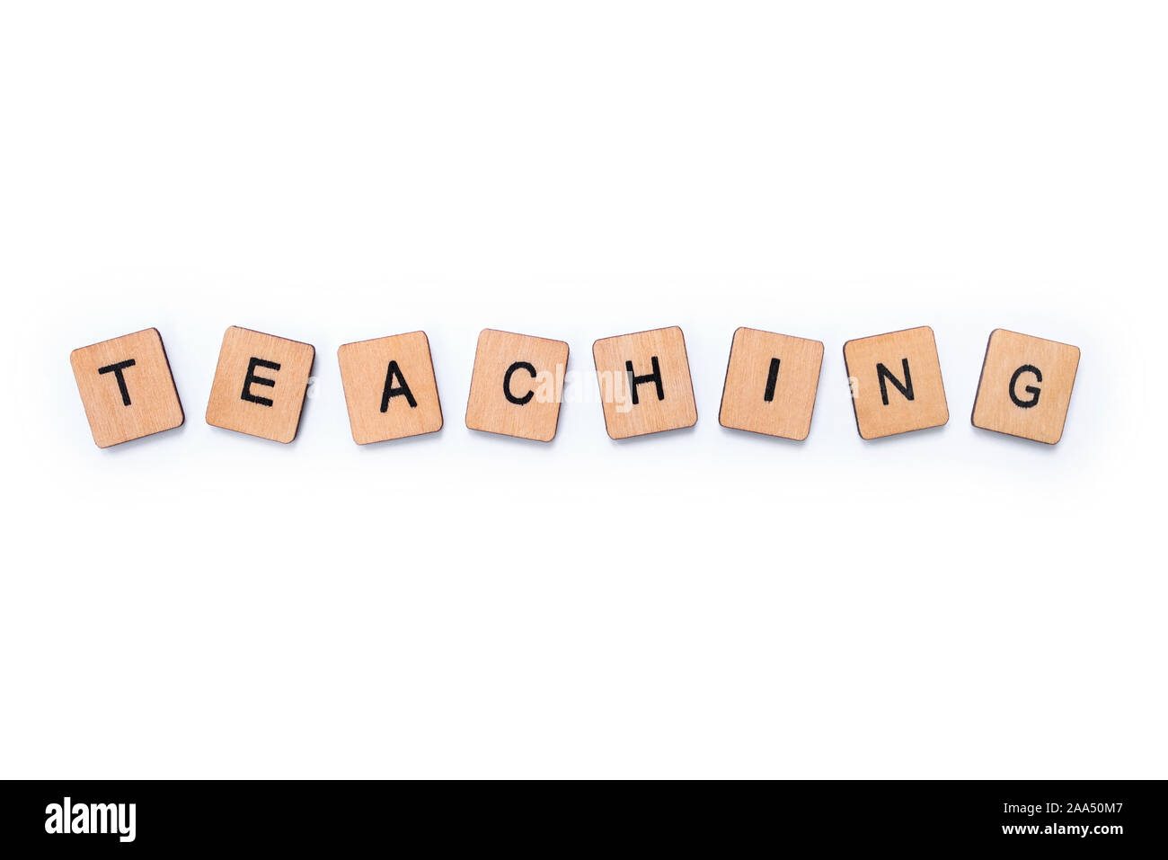 The word TEACHING, spelt with wooden letter tiles over a white ...