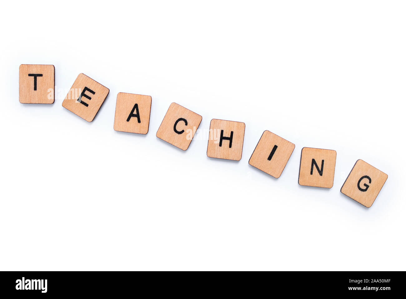 The word TEACHING, spelt with wooden letter tiles over a white ...