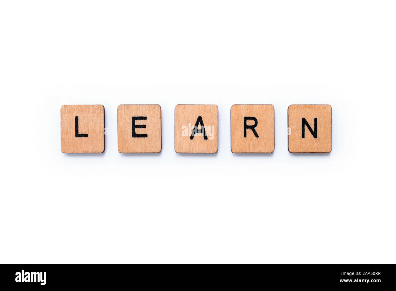 The word LEARN, spelt with wooden letter tiles over a white background ...