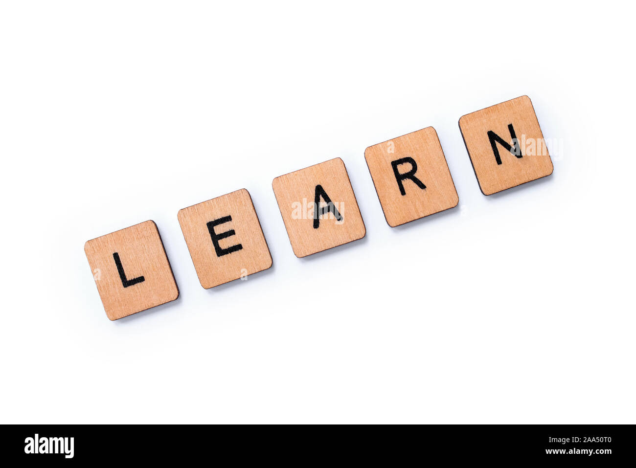 The word LEARN, spelt with wooden letter tiles over a white background ...