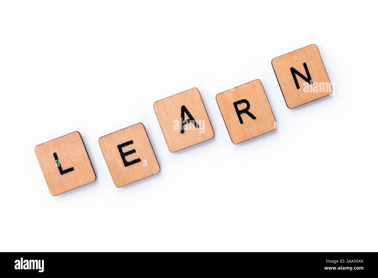 The word LEARN, spelt with wooden letter tiles over a white background ...