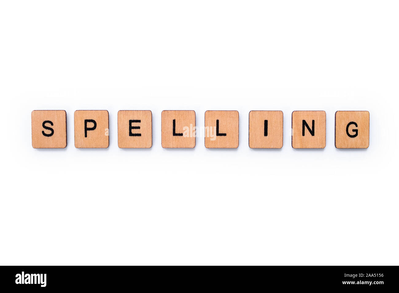 The word SPELLING, spelt with wooden letter tiles over a white ...