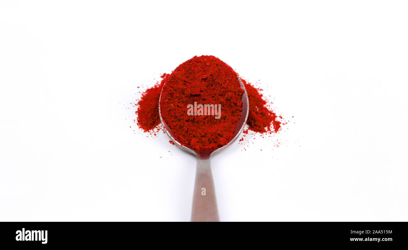 Red chili powder in metal spoon on white background. Top view with copy ...