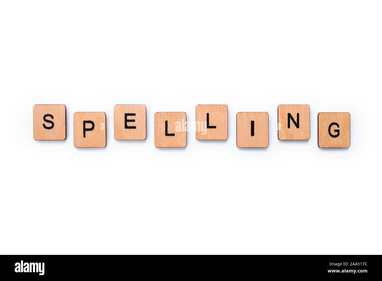 The word SPELLING, spelt with wooden letter tiles over a white ...