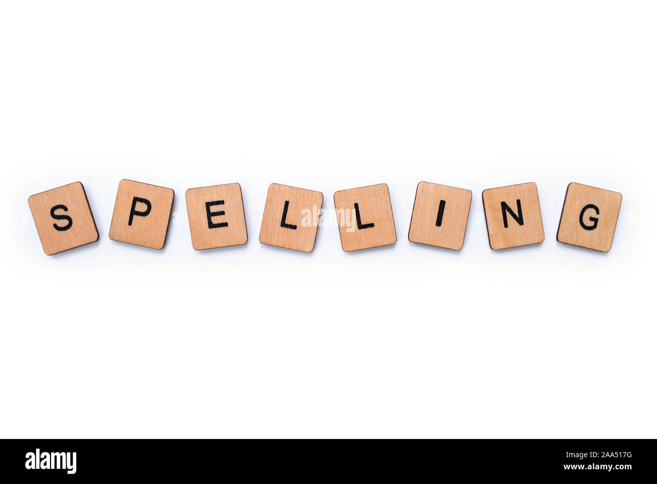 The word SPELLING, spelt with wooden letter tiles over a white ...