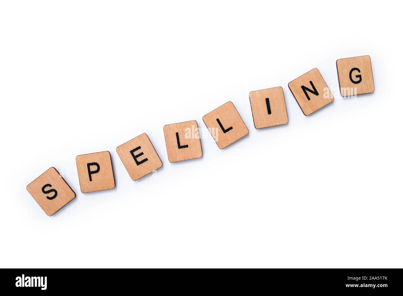 The word SPELLING, spelt with wooden letter tiles over a white ...