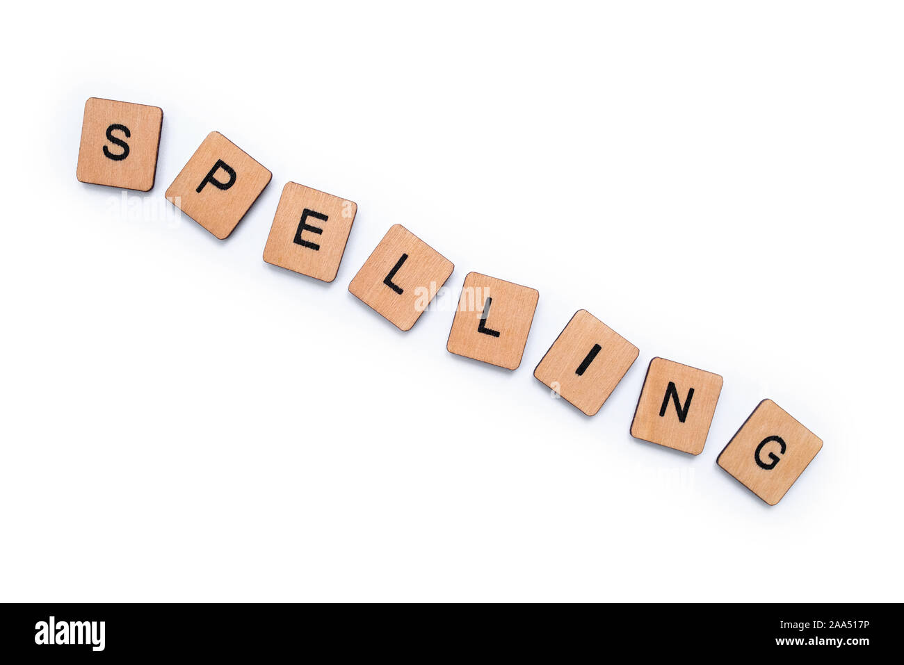 The word SPELLING, spelt with wooden letter tiles over a white ...