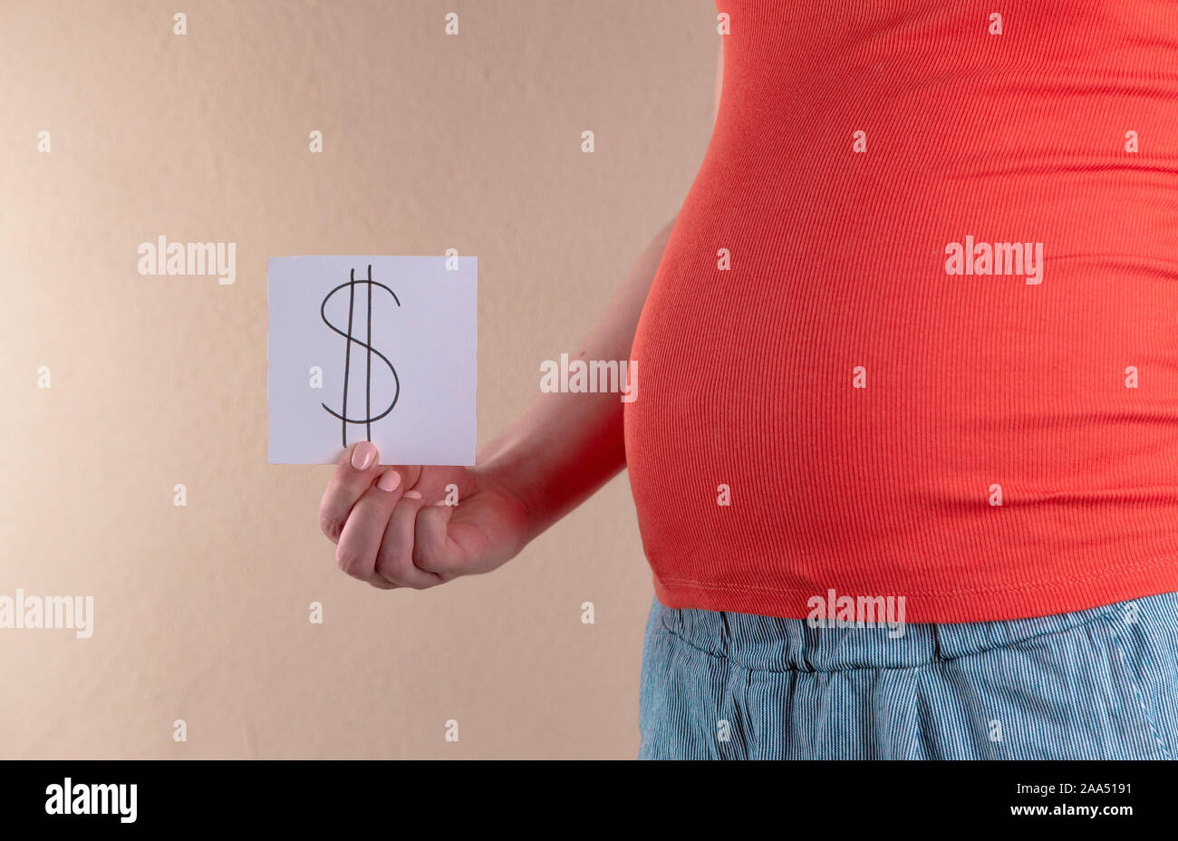 A close-up view of the belly of a pregnant woman in red who is holding ...