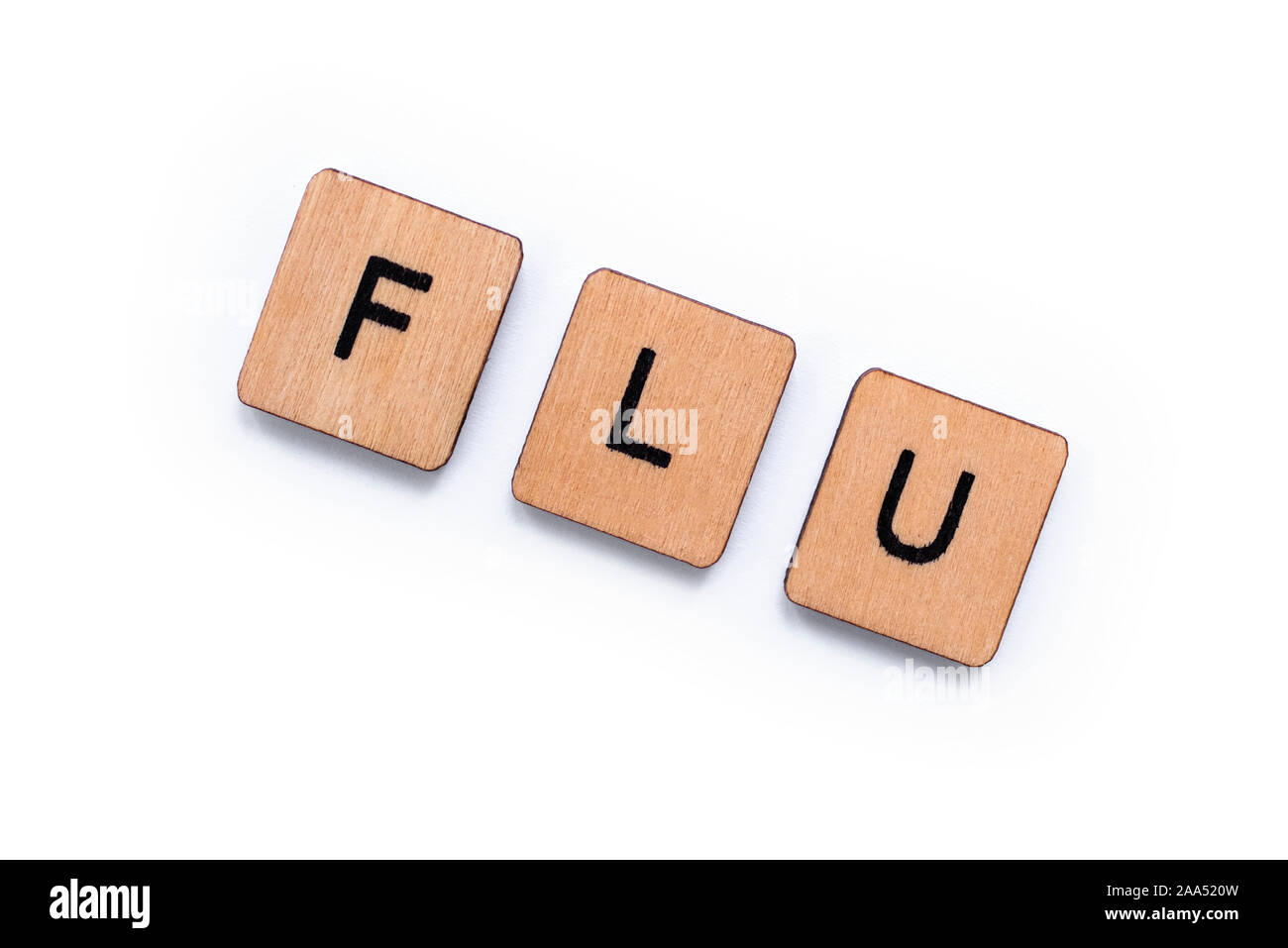 The word FLU, spelt with wooden letter tiles over a white background ...