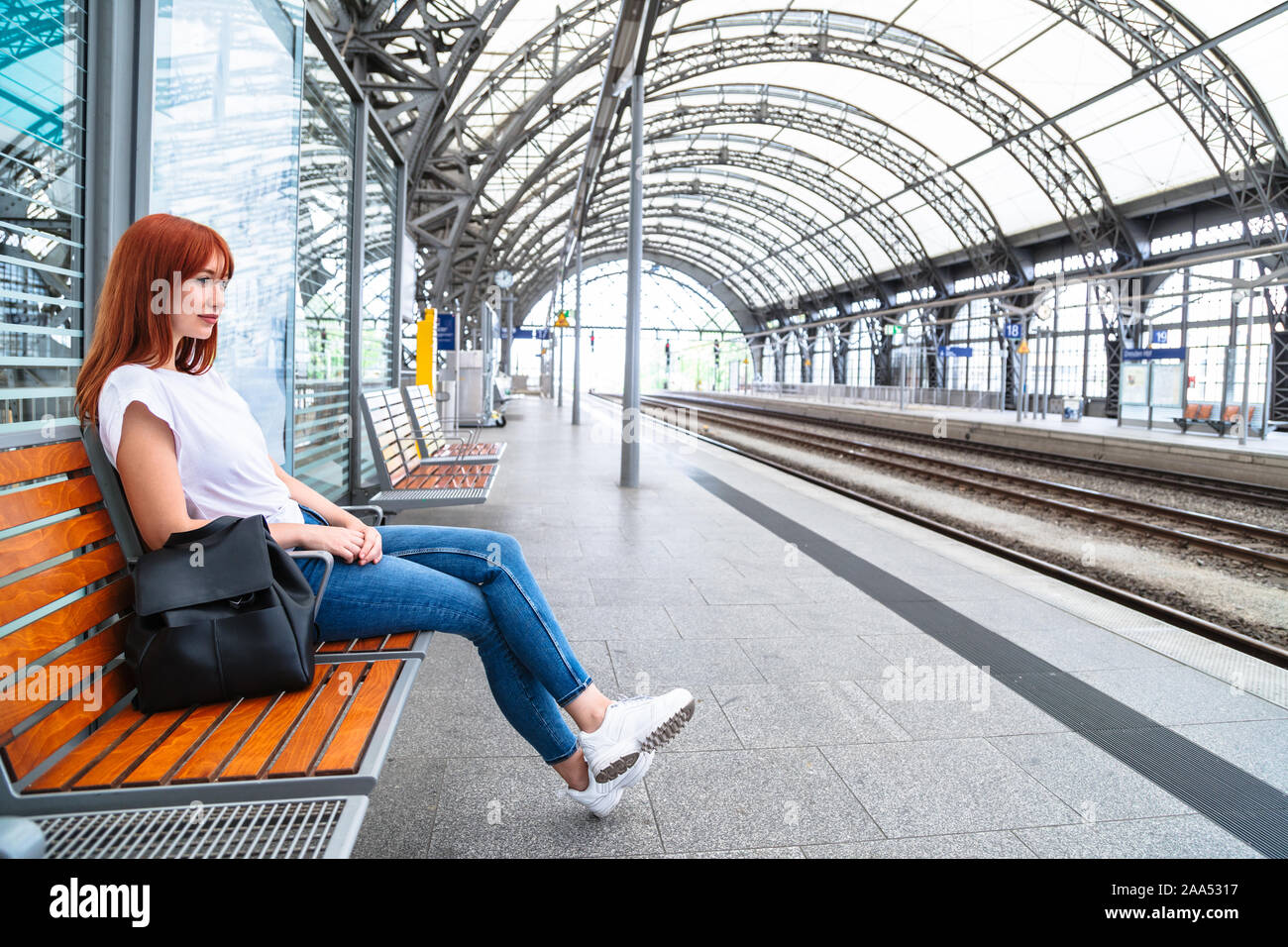 Girl waiting for train at station sitting on bench Stock Photo - Alamy