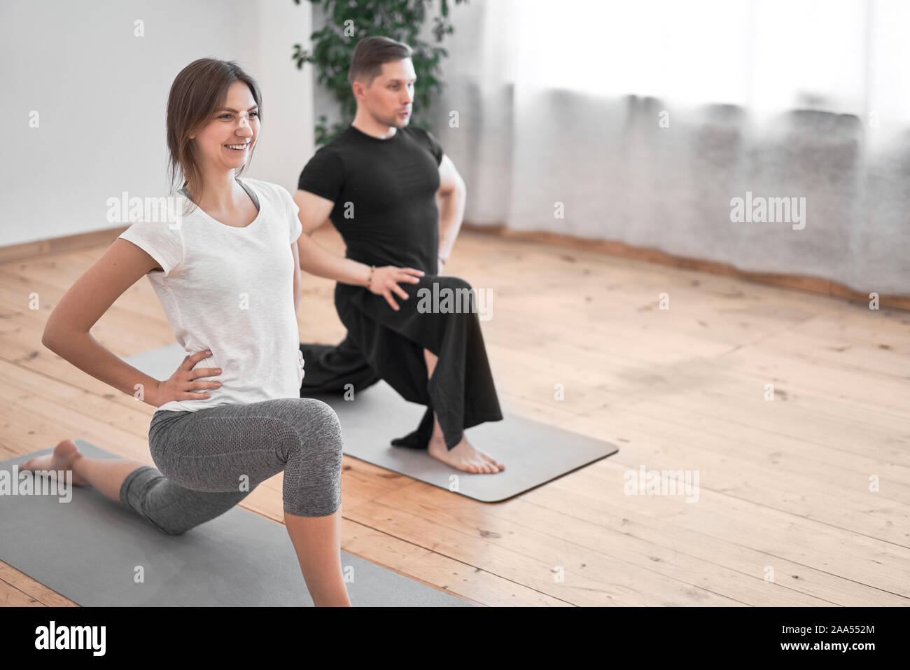 Man and woman doing yoga sitting in banarasan pose on gray rug against ...